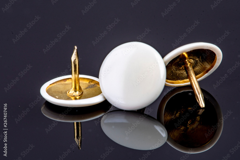 three white drawing pins on a black background with the tip pointing ...