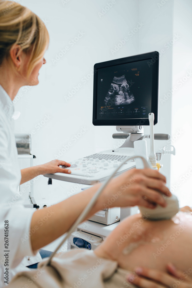 female doctor doing sonogram with pregnant woman at clinic. pregnant ...