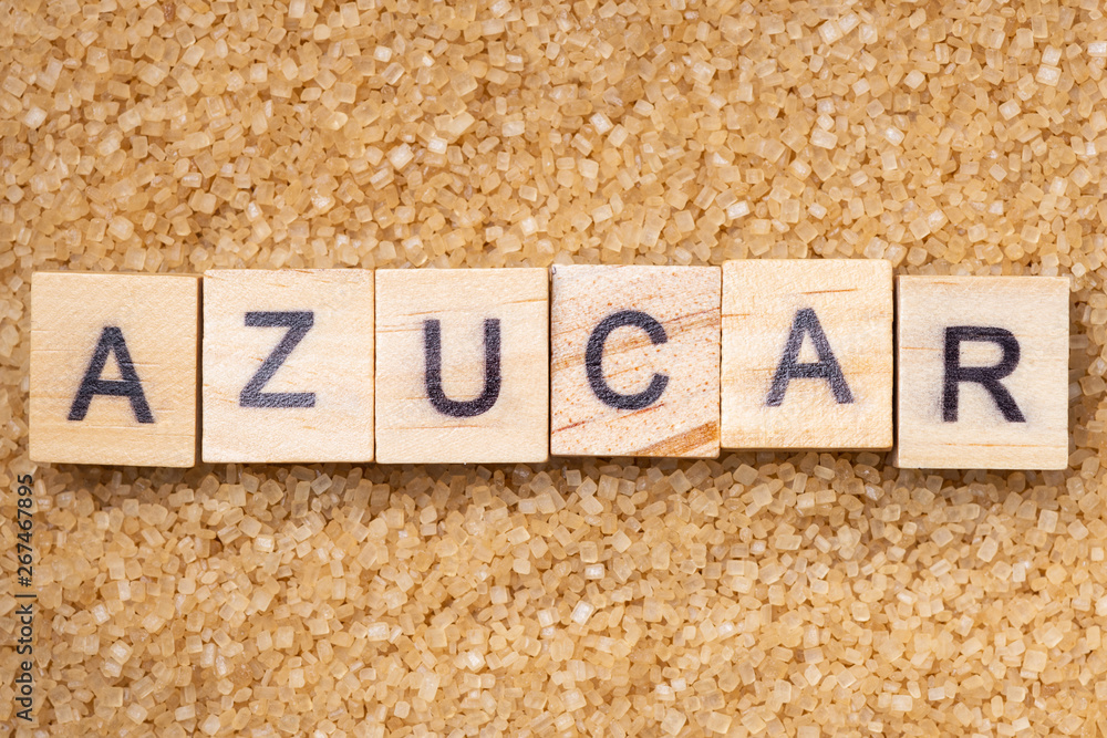 Word "azucar" on scrabble uppercase letters over a brown sugar surface ...