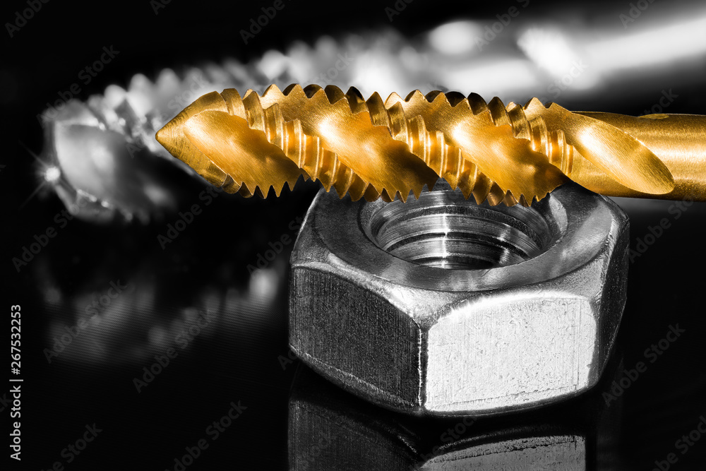 Stainless nut. Steel tap drill coated by titanium. Artistic detail ...