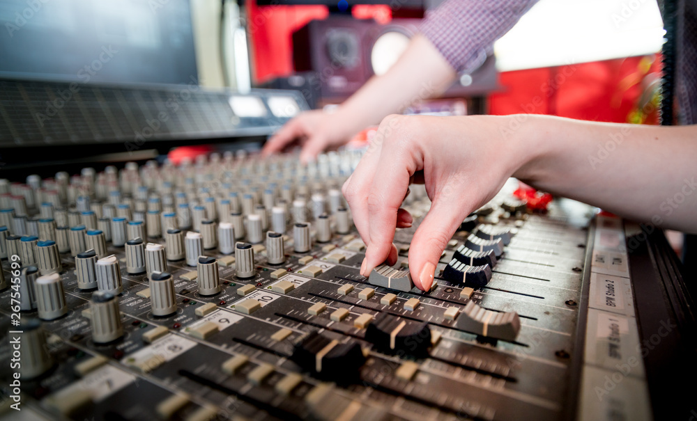 Music engineers working together in recording studio using mixing desk ...