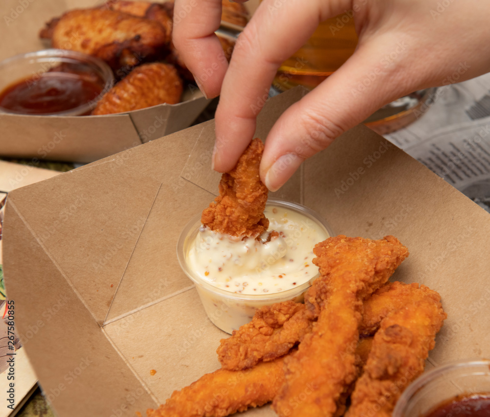 Mano mojando pollo frito en salsa blanca sobre mesa Stock Photo | Adobe ...