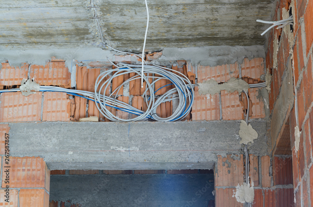 Electricity wire instalation in brick wall, construction site interior ...