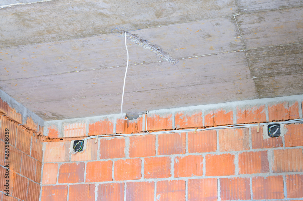 Electricity wire instalation in brick wall, construction site interior ...