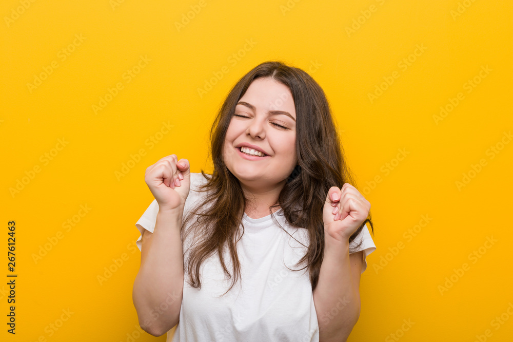 Young curvy plus size woman raising fist, feeling happy and successful ...