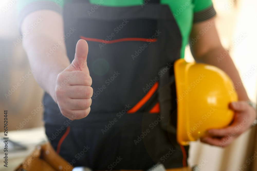 Hand of worker in yellow helmet show confirm sign with thumb up at arm ...