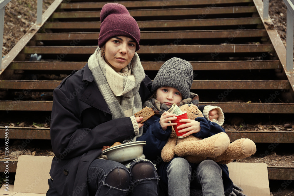 Poor mother and daughter with bread sitting on stairs outdoors Stock ...