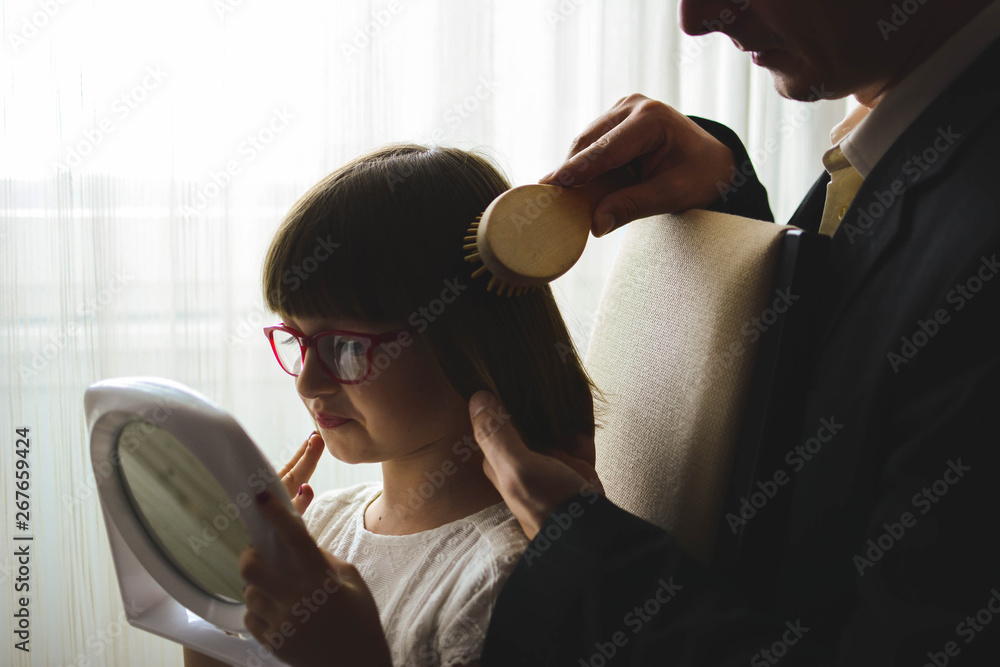 The father brush his daughter's hair in the morning before going to ...