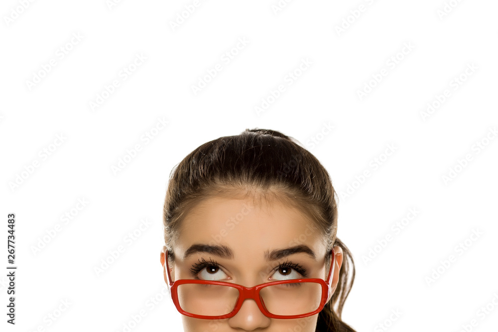 Young confused woman with glasses looking up on white background Stock ...