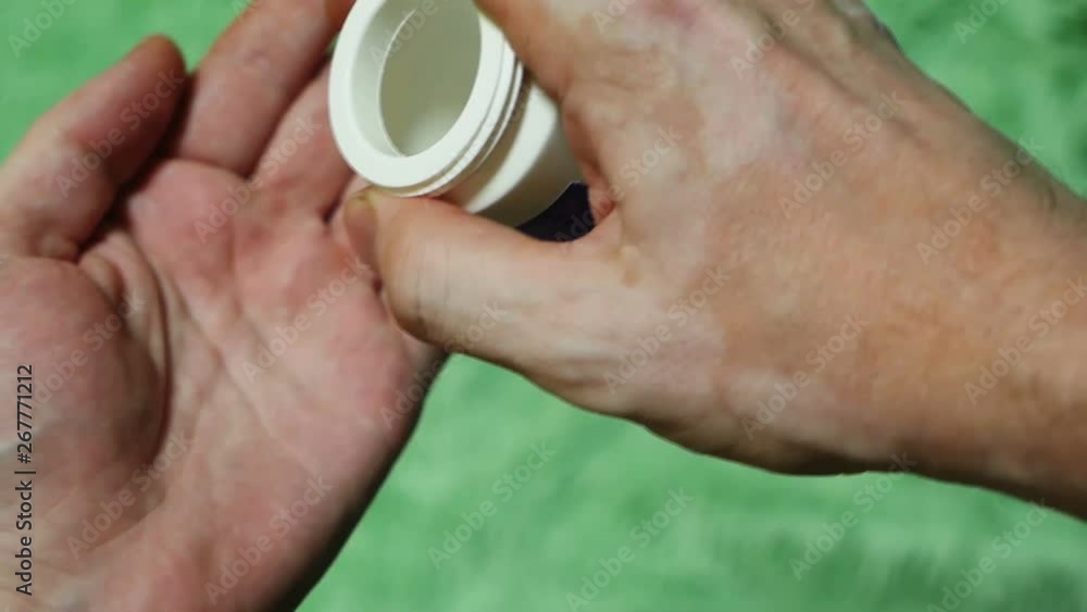 close up of two male hands pouring pills into the hand on the skin ...