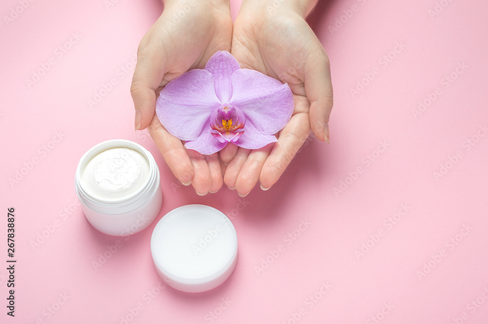 Mockup for hand skin care natural cosmetics. Woman hold orchid flower ...