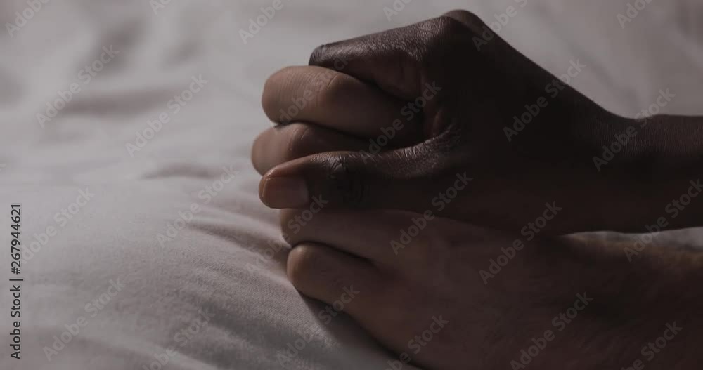 Multi-ethnic couple in love lying in bed together. Close up. Mans hand ...
