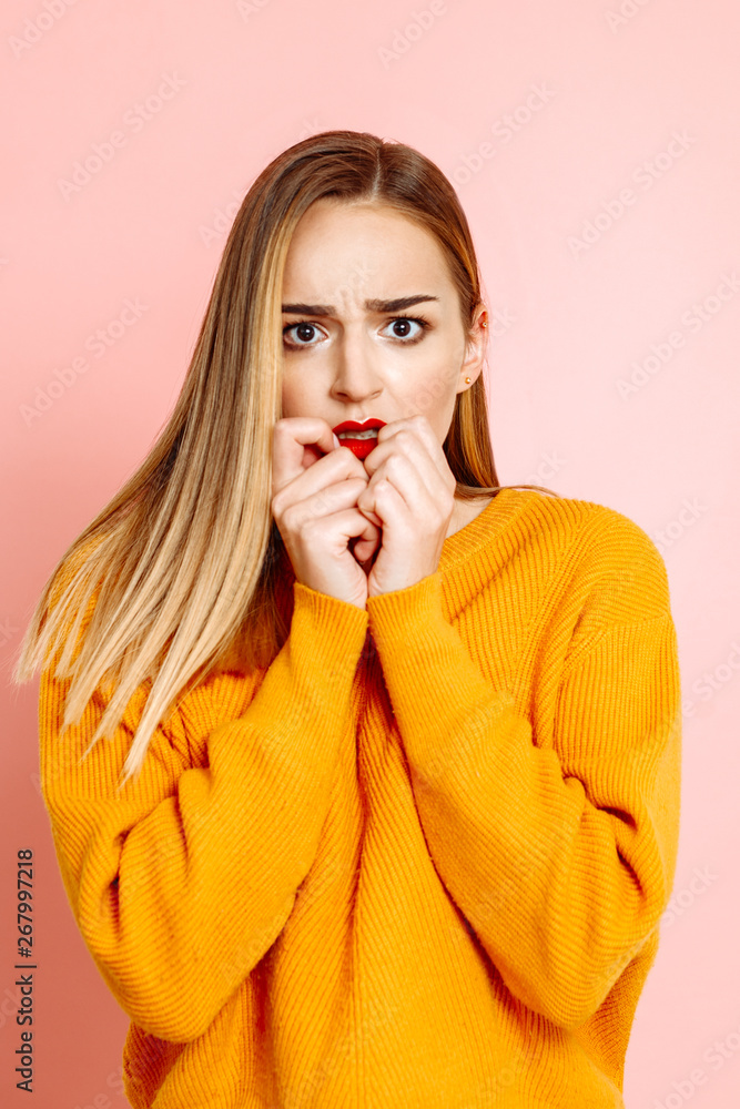 Human emotion. Portrait of a young blonde girl posing in a yellow ...