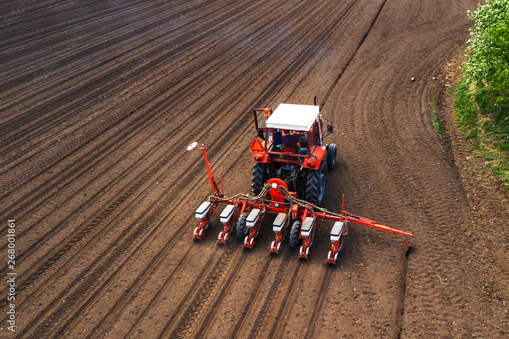 Aerial view of tractor with mounted seeder performing direct seeding ...
