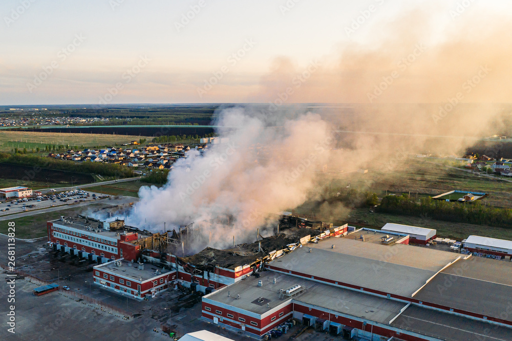 Burning industrial building with fire, huge thick smoke and burnt roof ...