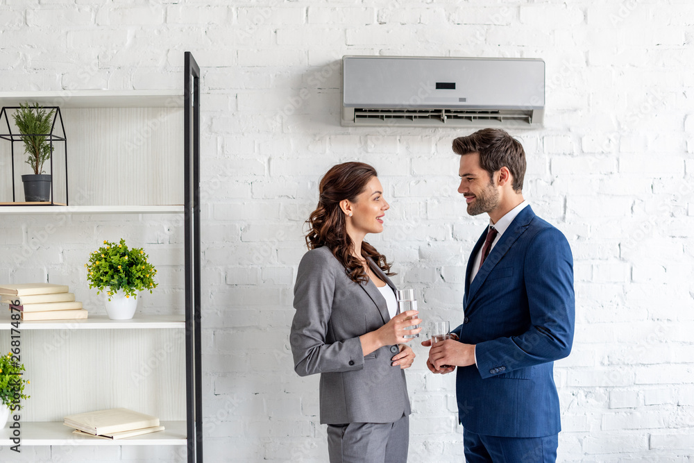 young smiling businesspeople talking while standing under air ...