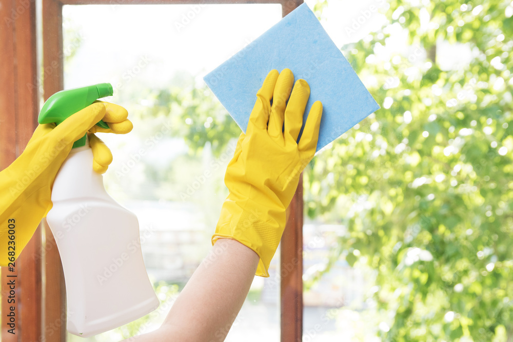 Girl housewife washes the windows in the house in yellow rubber gloves ...