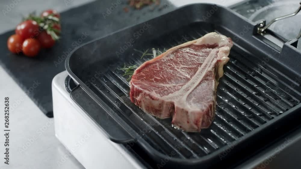 Fresh steak cooking at griddle pan. Closeup raw beef grilling at cast ...