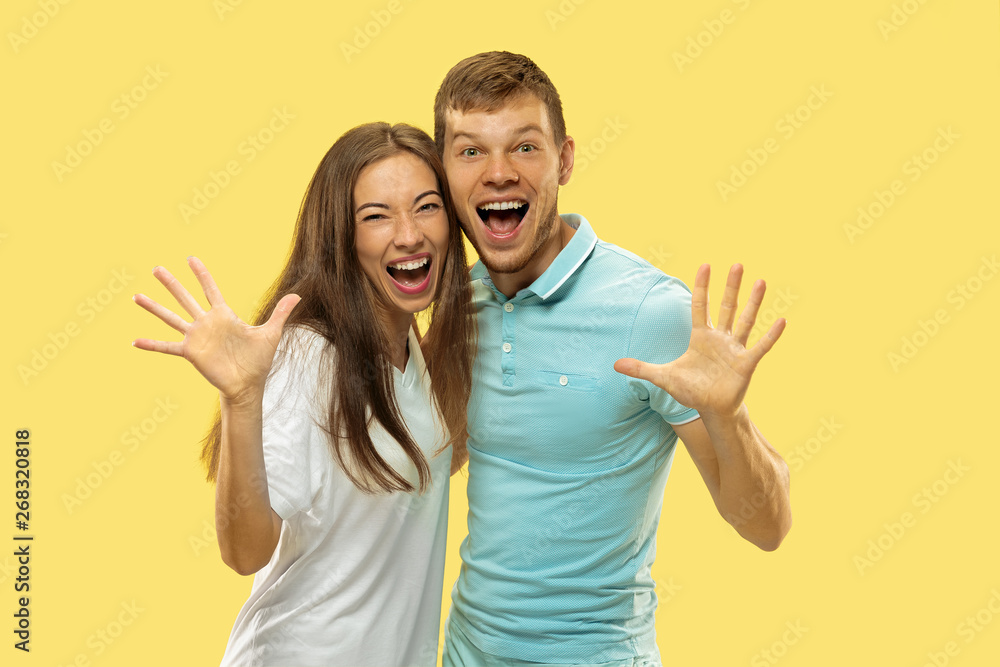 Beautiful young couple's half-length portrait on yellow studio ...