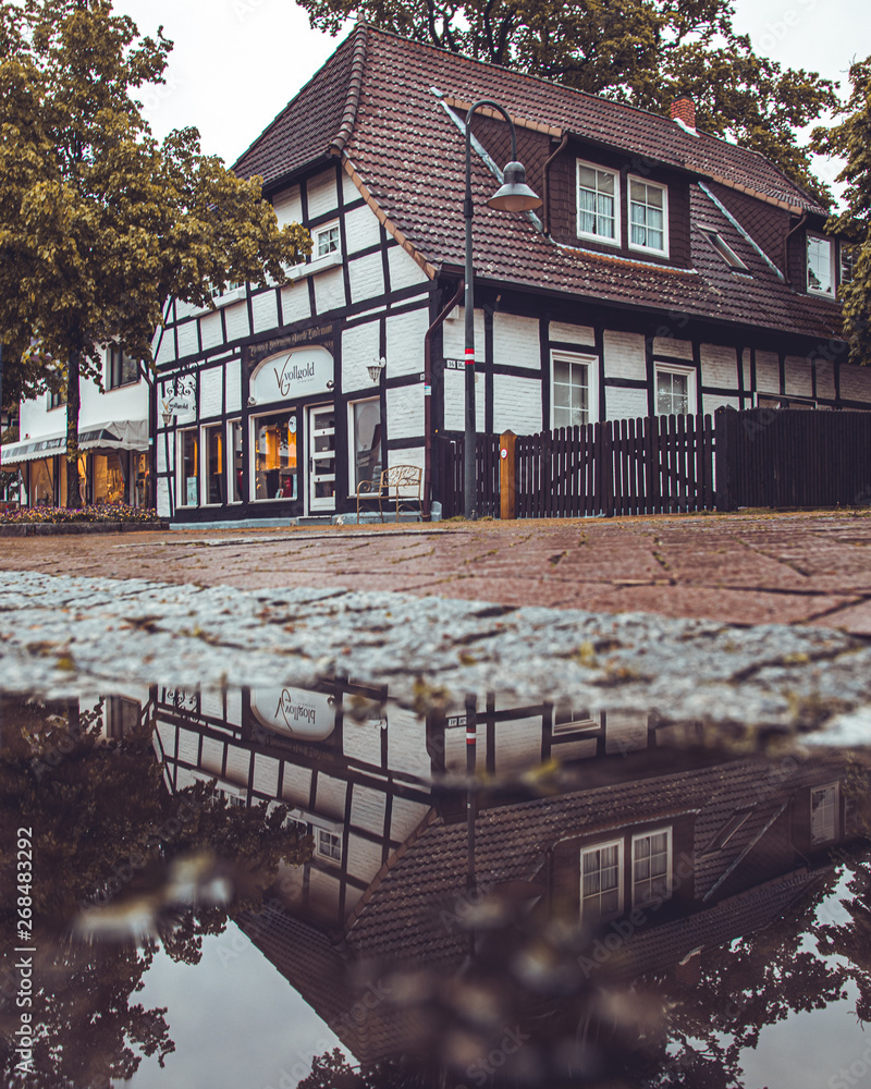 Half timbered house in a town street with reflection from a big puddle ...