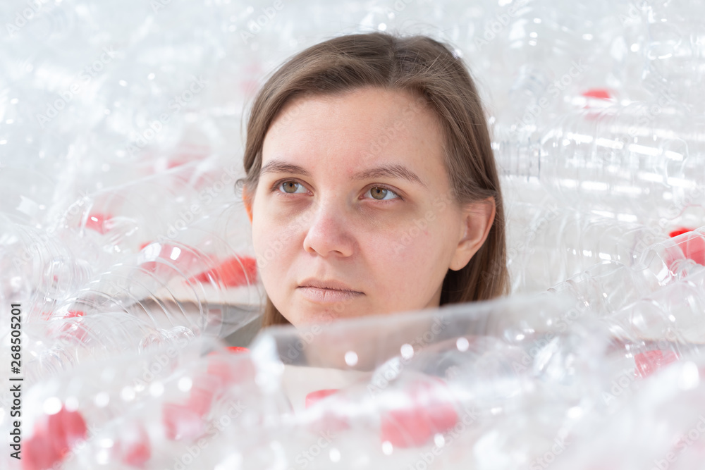 Dehydrated sick woman is lying in a pile of plastic bottles ...