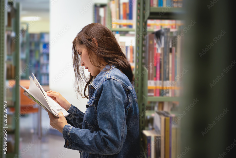 Asian Student searching for textbook in the bookshelf in the ...