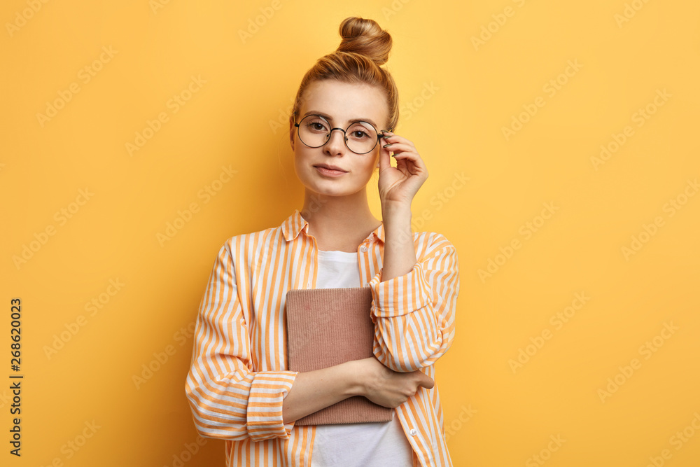 clever cute awesome woman holding a book, touching her glasses and ...
