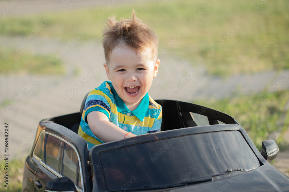 Cute boy riding on black electric car in the park. Funny boy rides on a ...