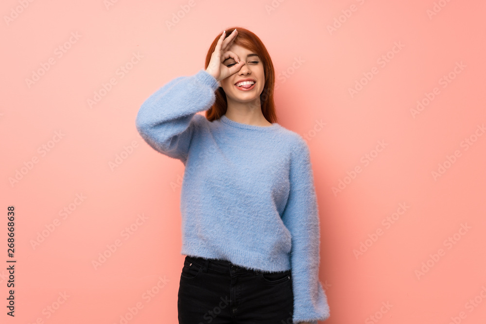 Young redhead woman over pink background makes funny and crazy face ...