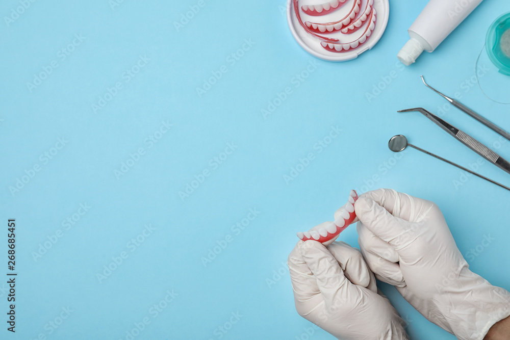 Dentist holding tooth prosthesis on color background, top view. Space ...