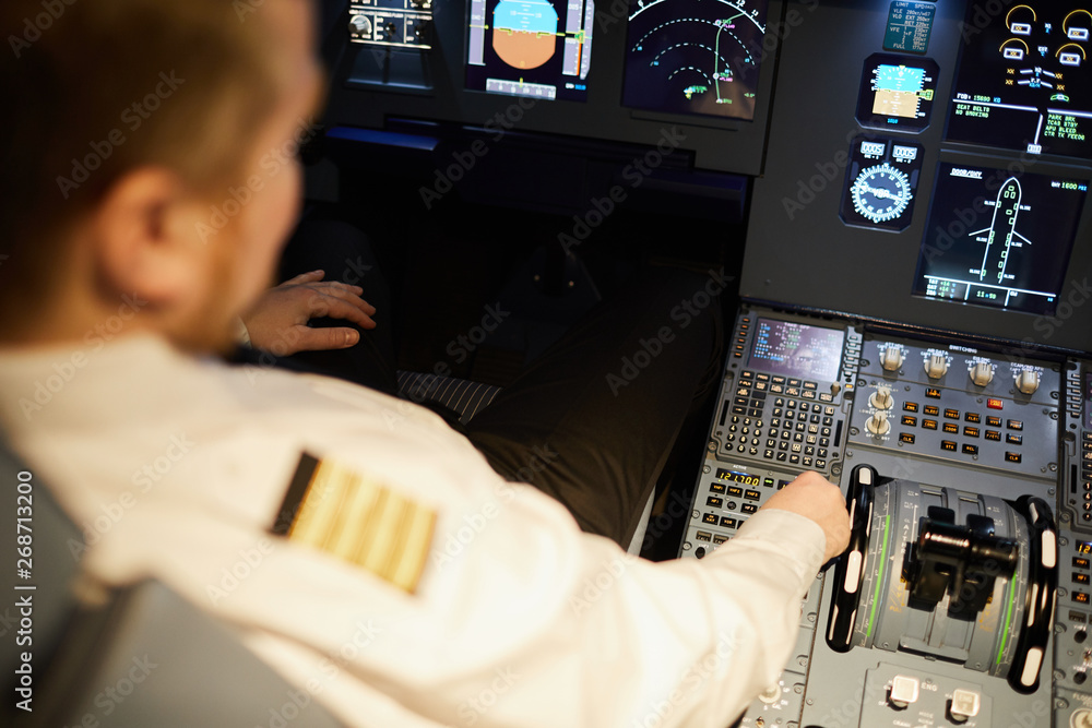 Close-up of airline pilot in uniform sitting at control panel of ...