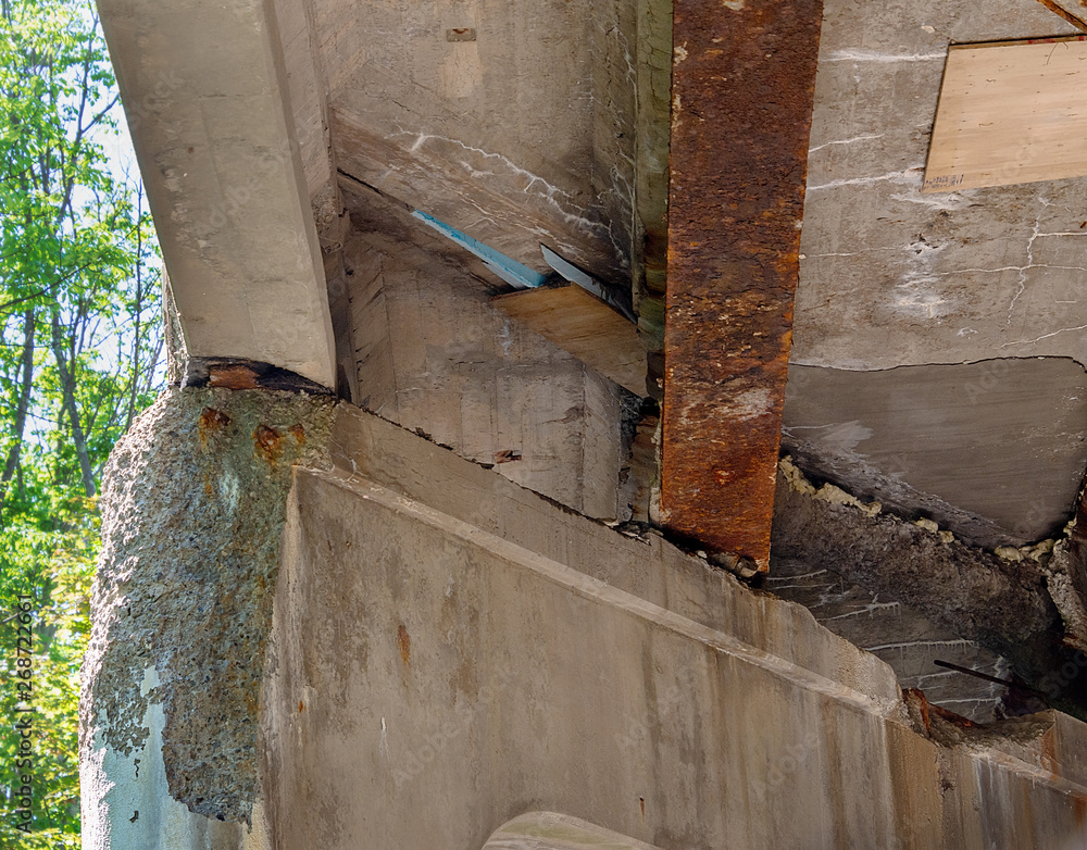 The underside of a highway bridge showing crumbling cement rusting ...
