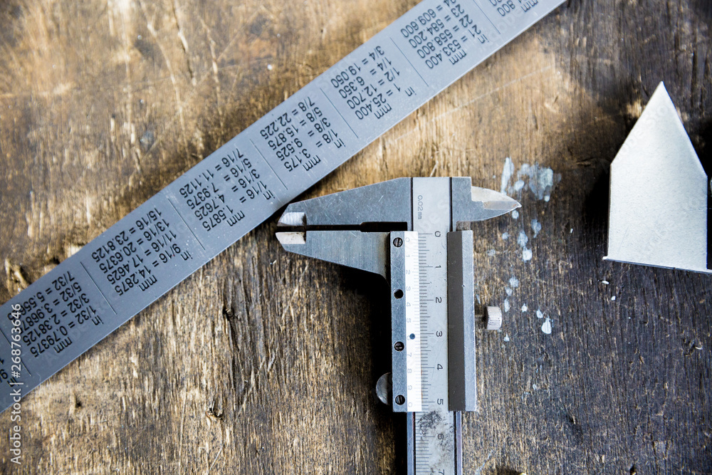 Vernier caliper and metal meter ruler on oil stained table, measuring ...