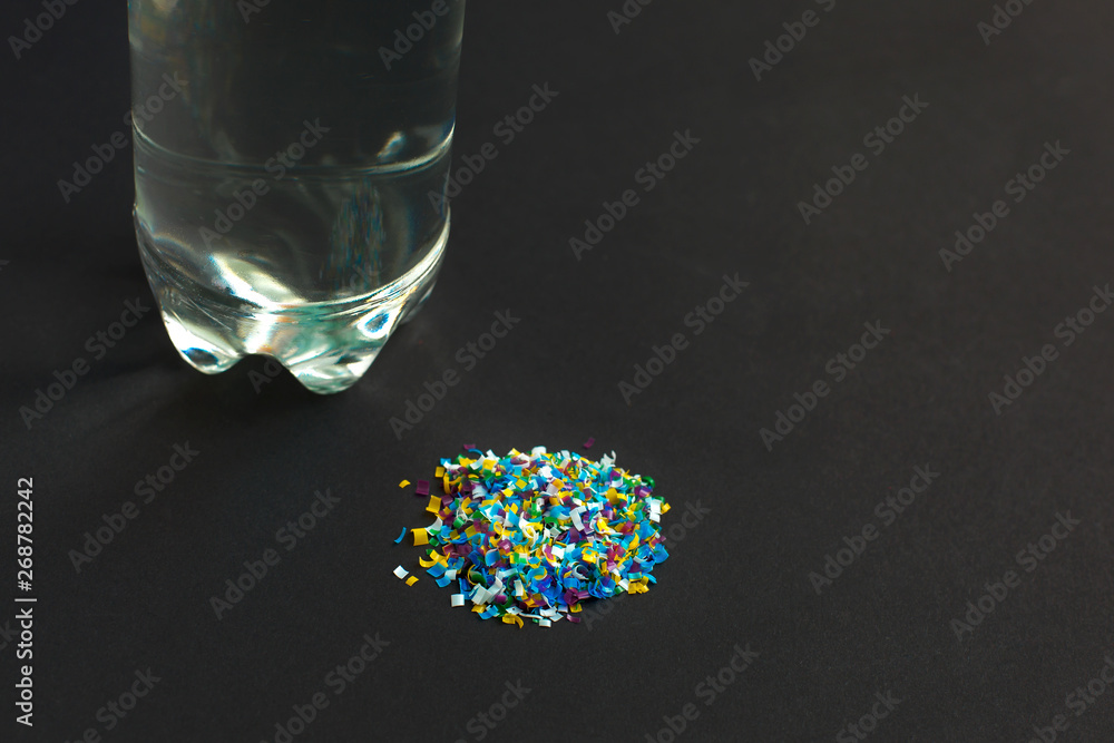 Microplastic contaminated water in the bottle. A pile of microplastic ...
