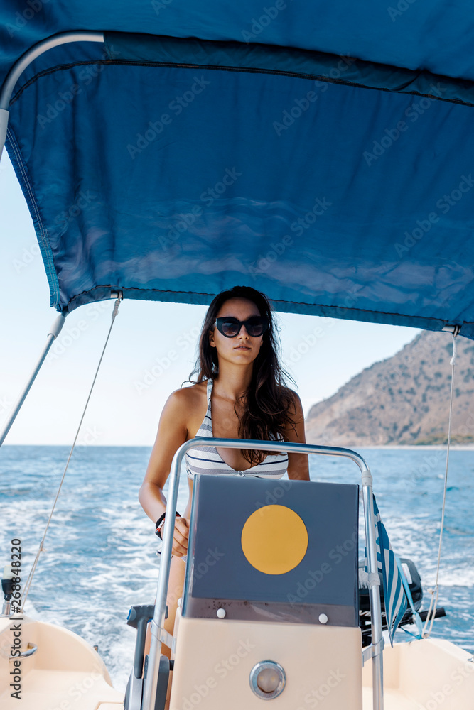 Beautiful woman in bikini sailing a motorboat Stock Photo | Adobe Stock