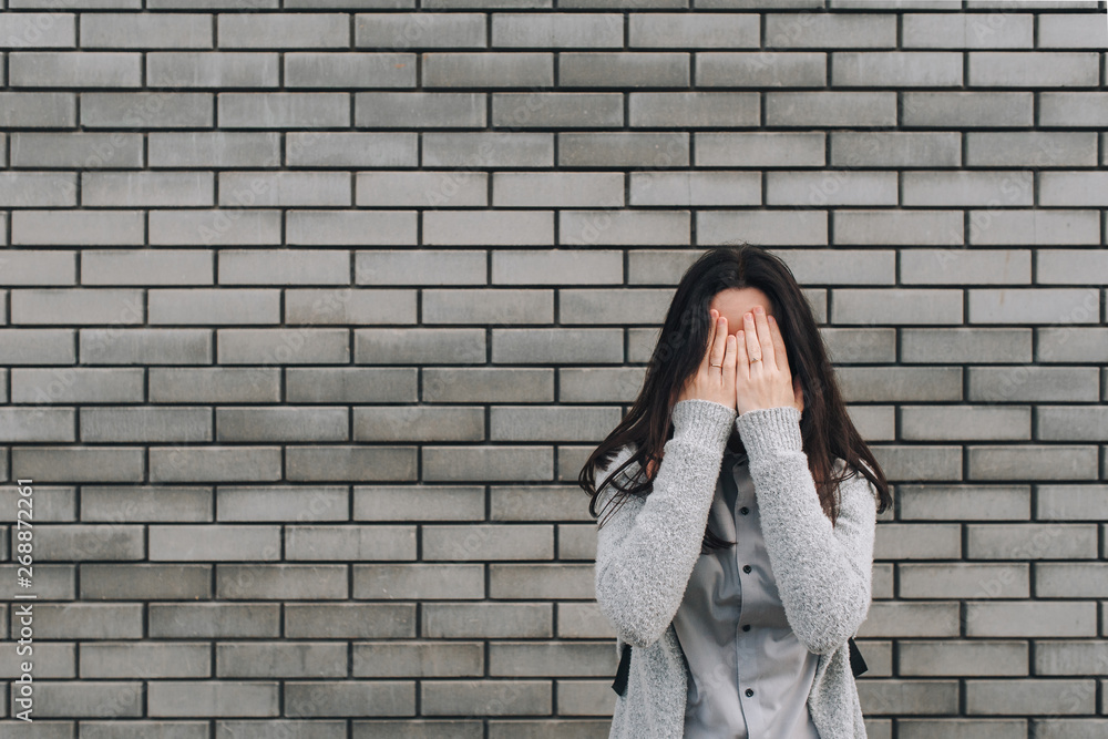 Beautiful young woman on the gray background with sad expression ...