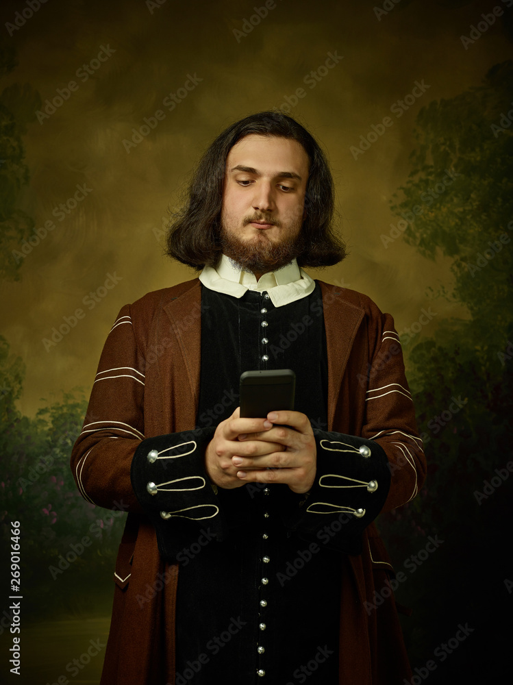Young man as a medieval knight on dark studio background. Portrait in ...