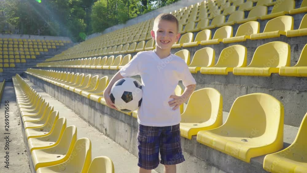 Boy with a soccer ball in the stands of the stadium. A young footballer ...