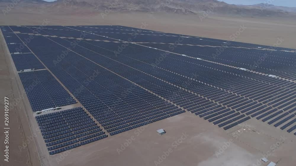 Aerial footage of hundreds solar energy modules or panels rows along the dry lands at Atacama ...