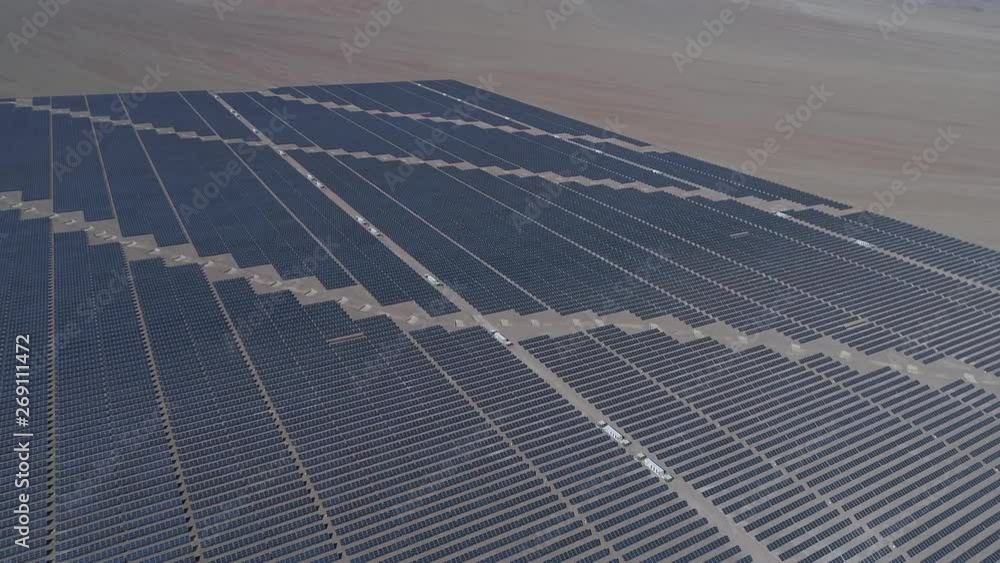 Aerial footage of hundreds solar energy modules or panels rows along the dry lands at Atacama ...