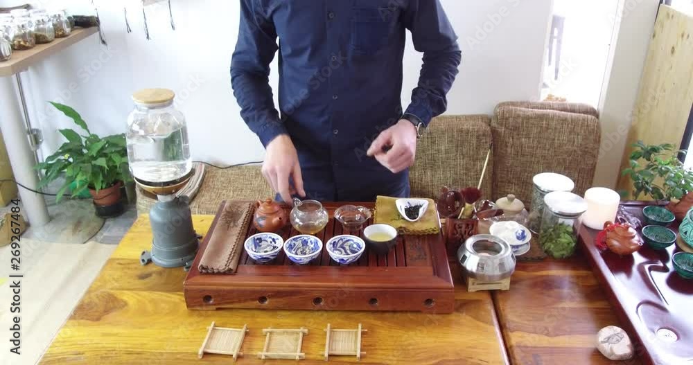Chinese tea tasting in the tea shop. The seller, dressed in European ...