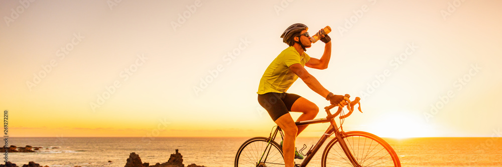 Triahtlon athlete man drinking water bottle on road racing bike ride ...