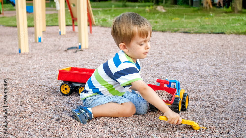 Portrait of cute 3 years old toddler boy sitting on the playground at ...
