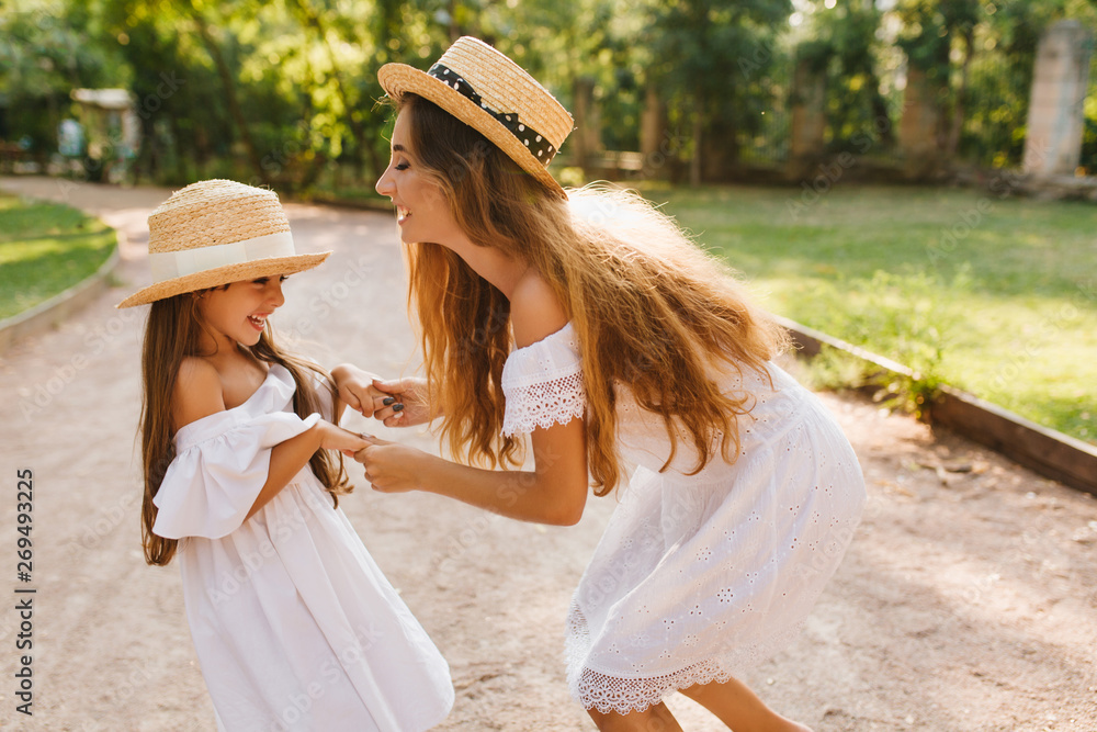 Laughing tanned woman bent over to smiling girl and dancing with her ...