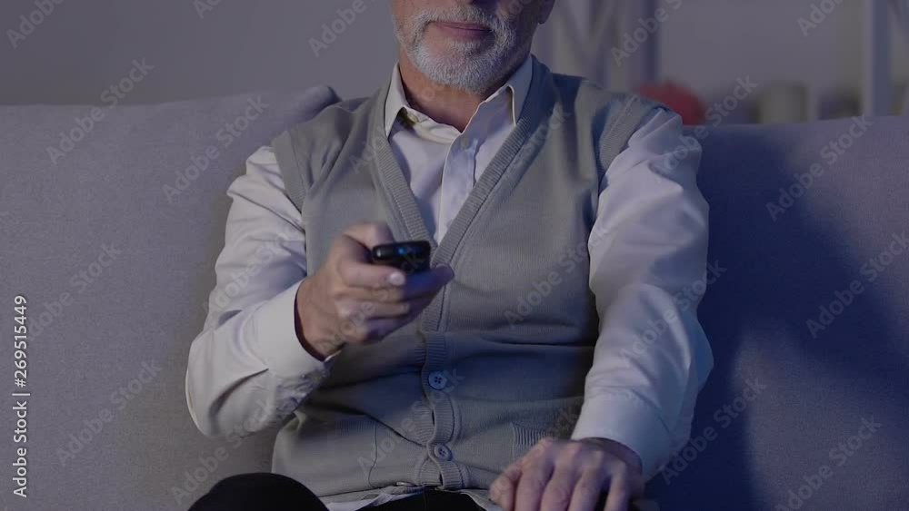 Bored old man switching channels at home, turning off TV, uninterested ...