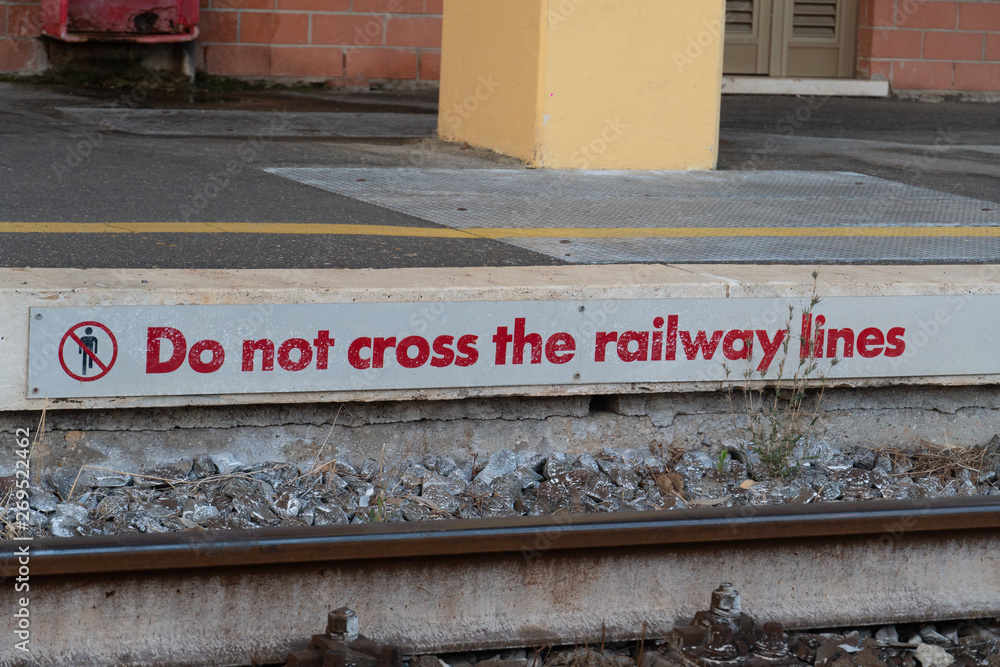 Warning sign in the railroad station: Do not cross the railway lines ...