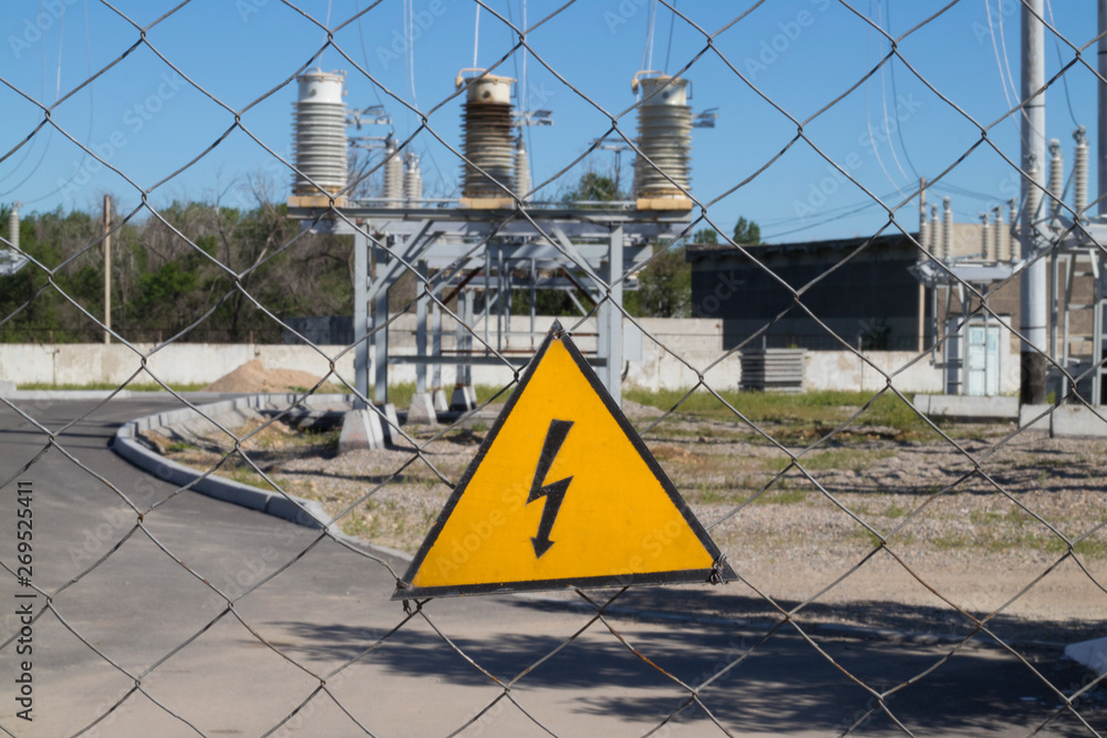 Foto de Electrical hazard sign on metal grid. On the background of ...