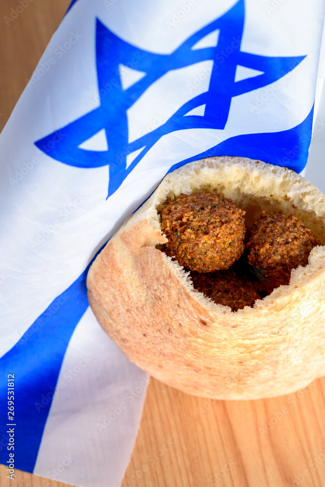 Falafel balls in a pita on wooden table over Israel flag background ...