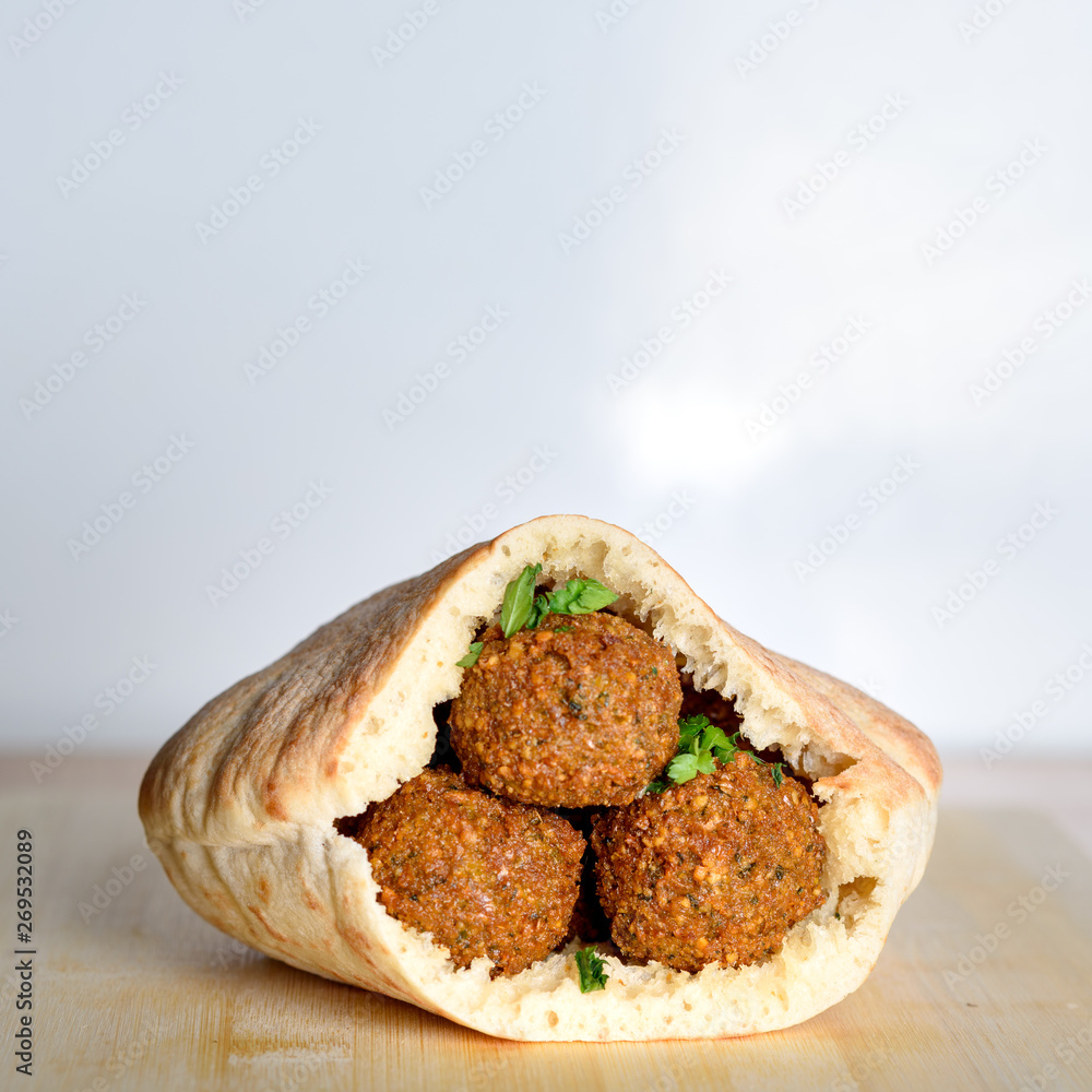 Falafel balls in a pita on wooden table over Israel flag background ...