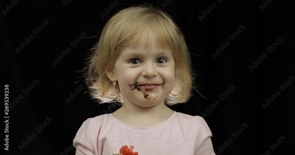 Child with dirty face from melted chocolate and whipped cream eats ...